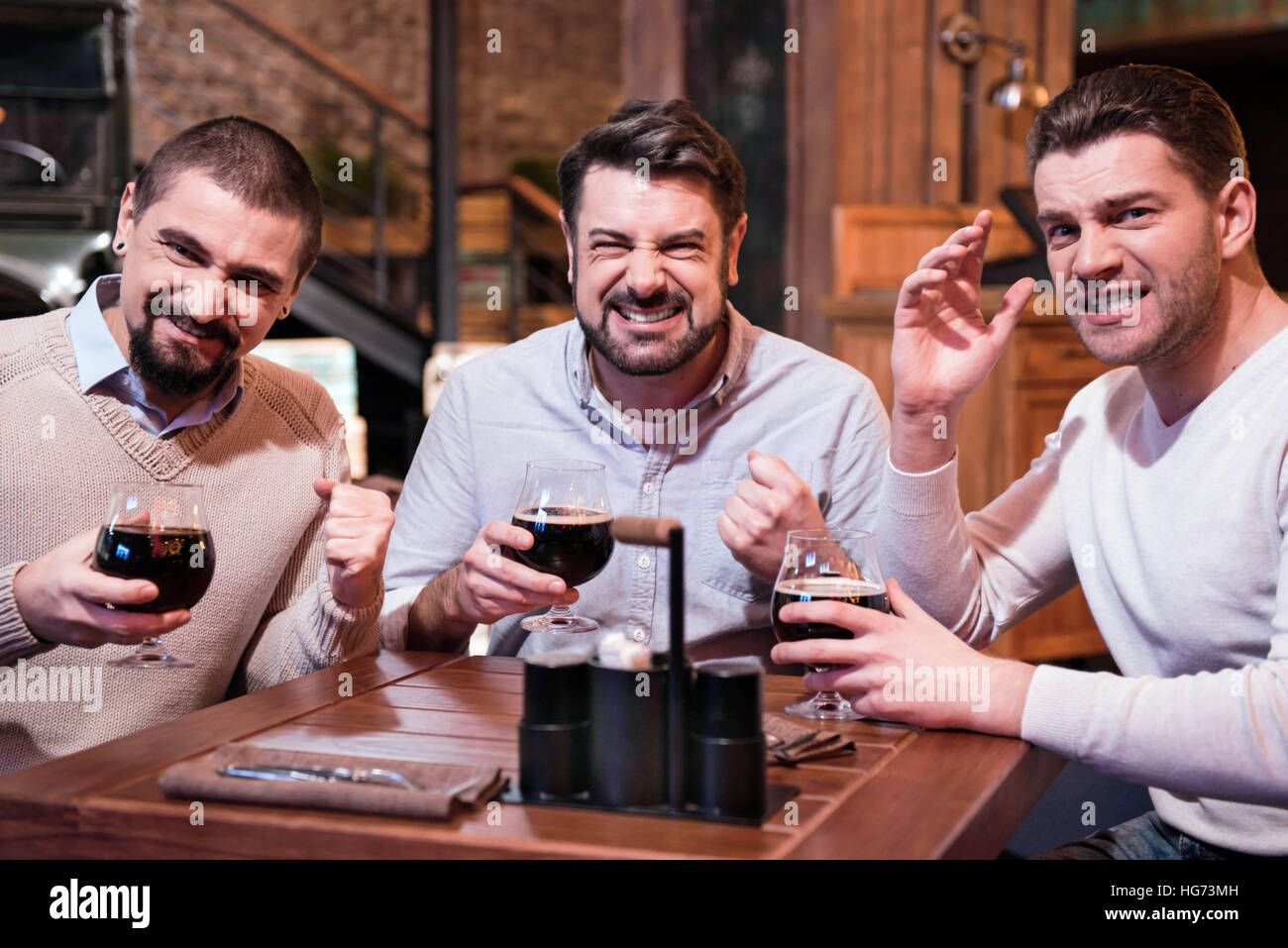 Positive joyful men supporting their football team Stock Photo - Alamy