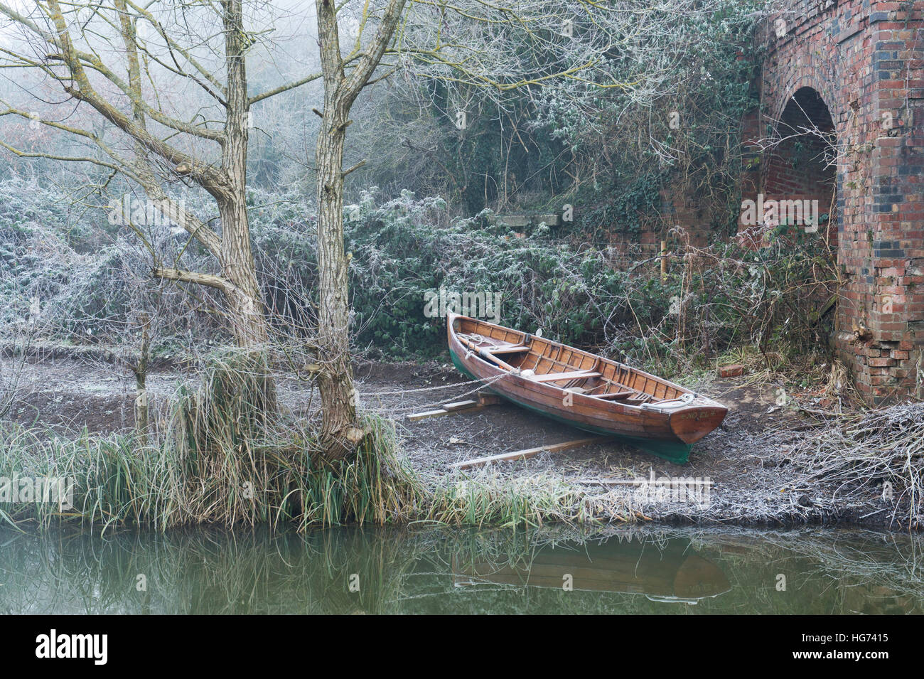 Wooden rowing boat by the Oxford canal on a frosty foggy December ...