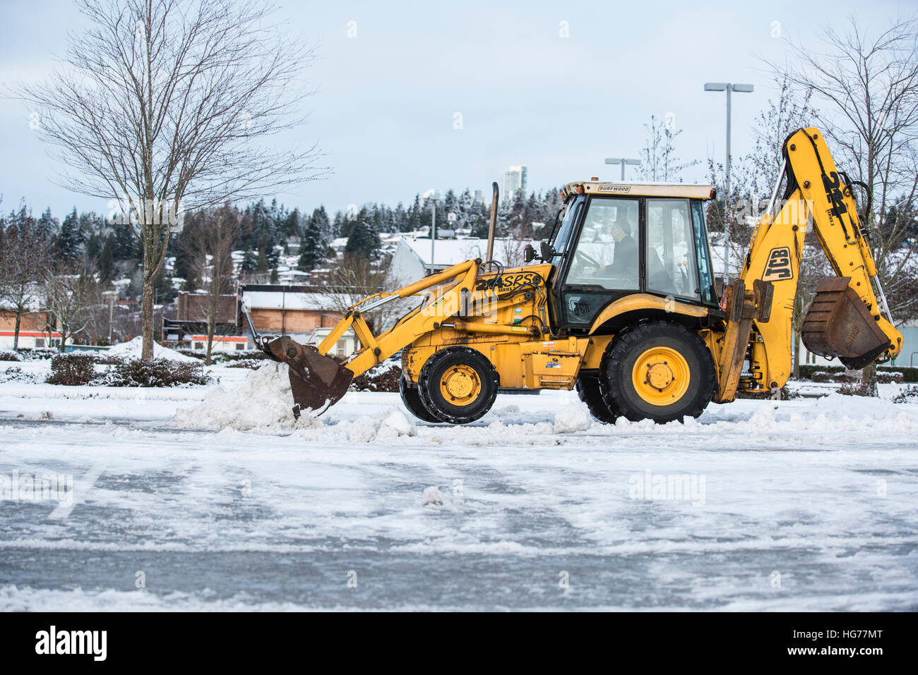 Backhoe clearing snow from a parking lot Stock Photo - Alamy