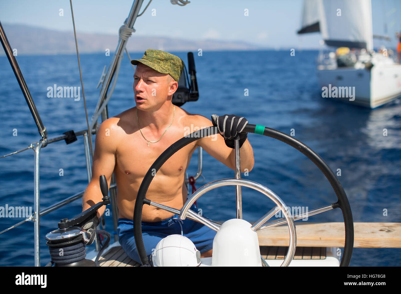 Skipper at the helm controls of a sailing boat during sea yacht race ...