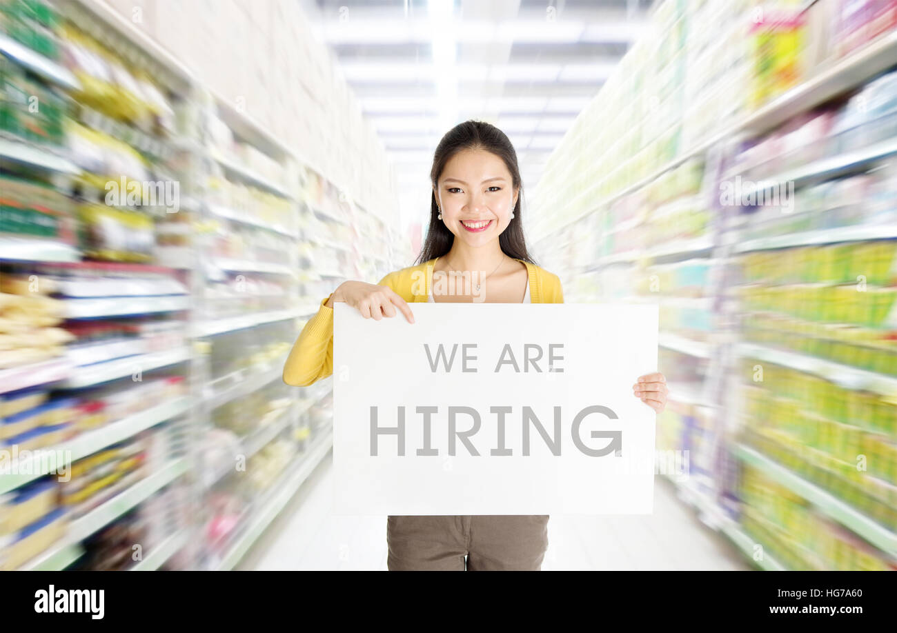 Young Asian woman hand holding "we are hiring" sign board in market or ...