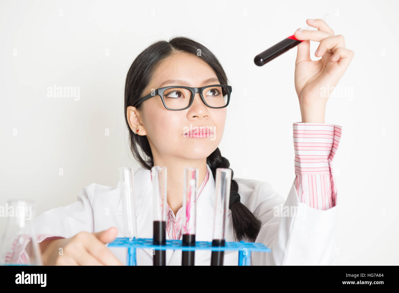 Young attractive Asian laboratory assistant checking the blood in tube ...