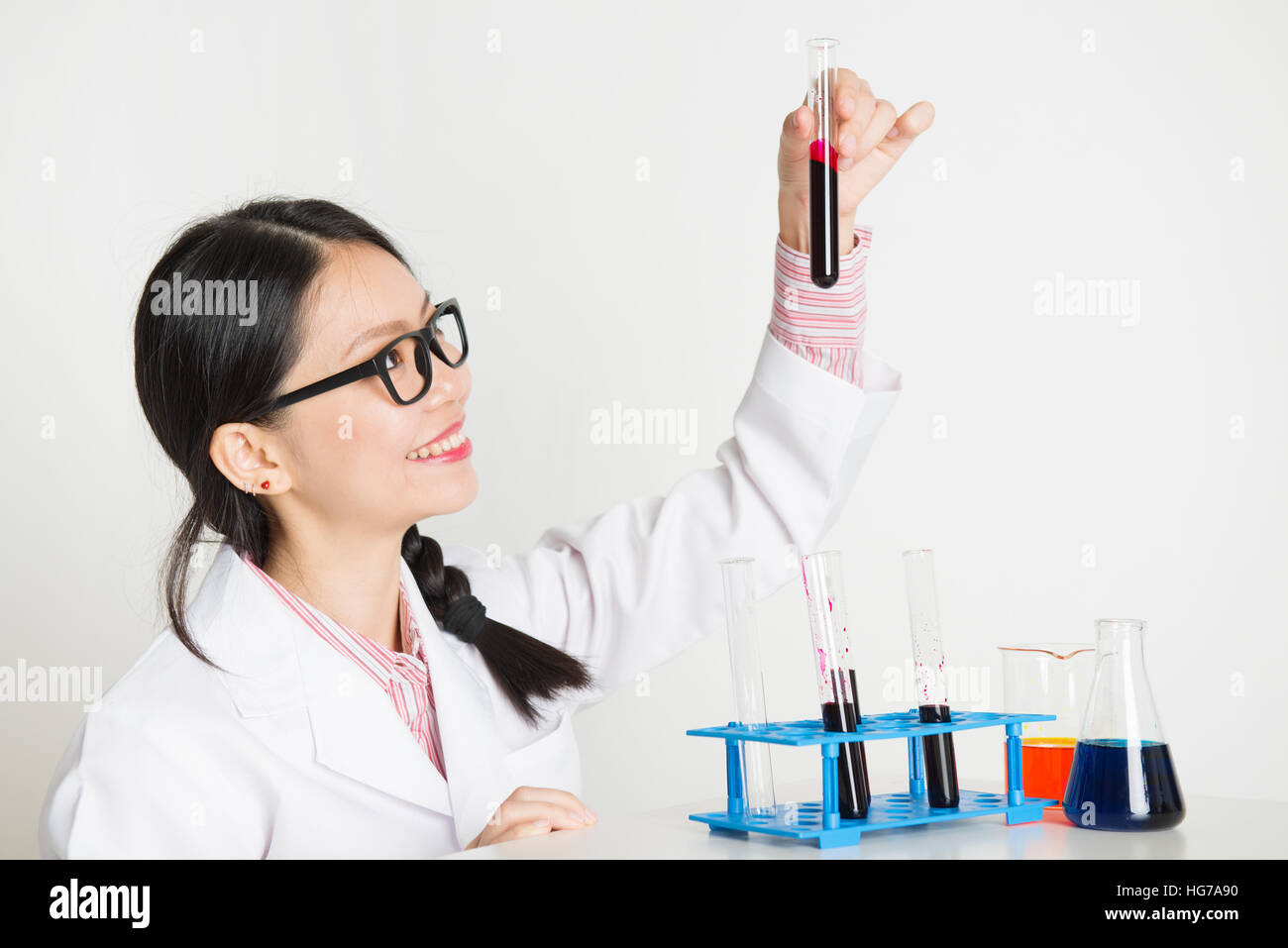 Attractive young Asian female researcher looking at the tube in ...