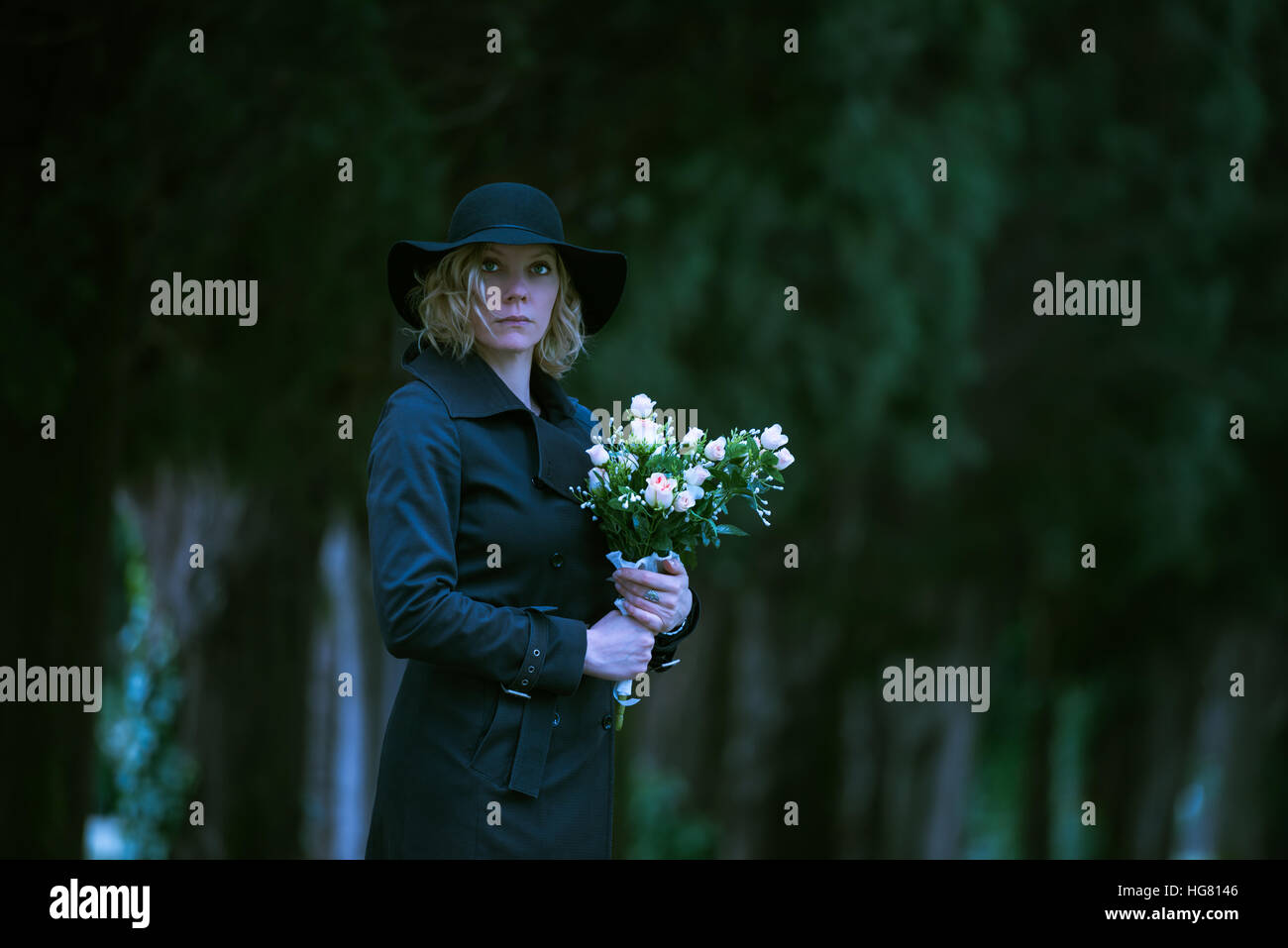 Portrait of a woman at cemetery holding flowers Stock Photo - Alamy