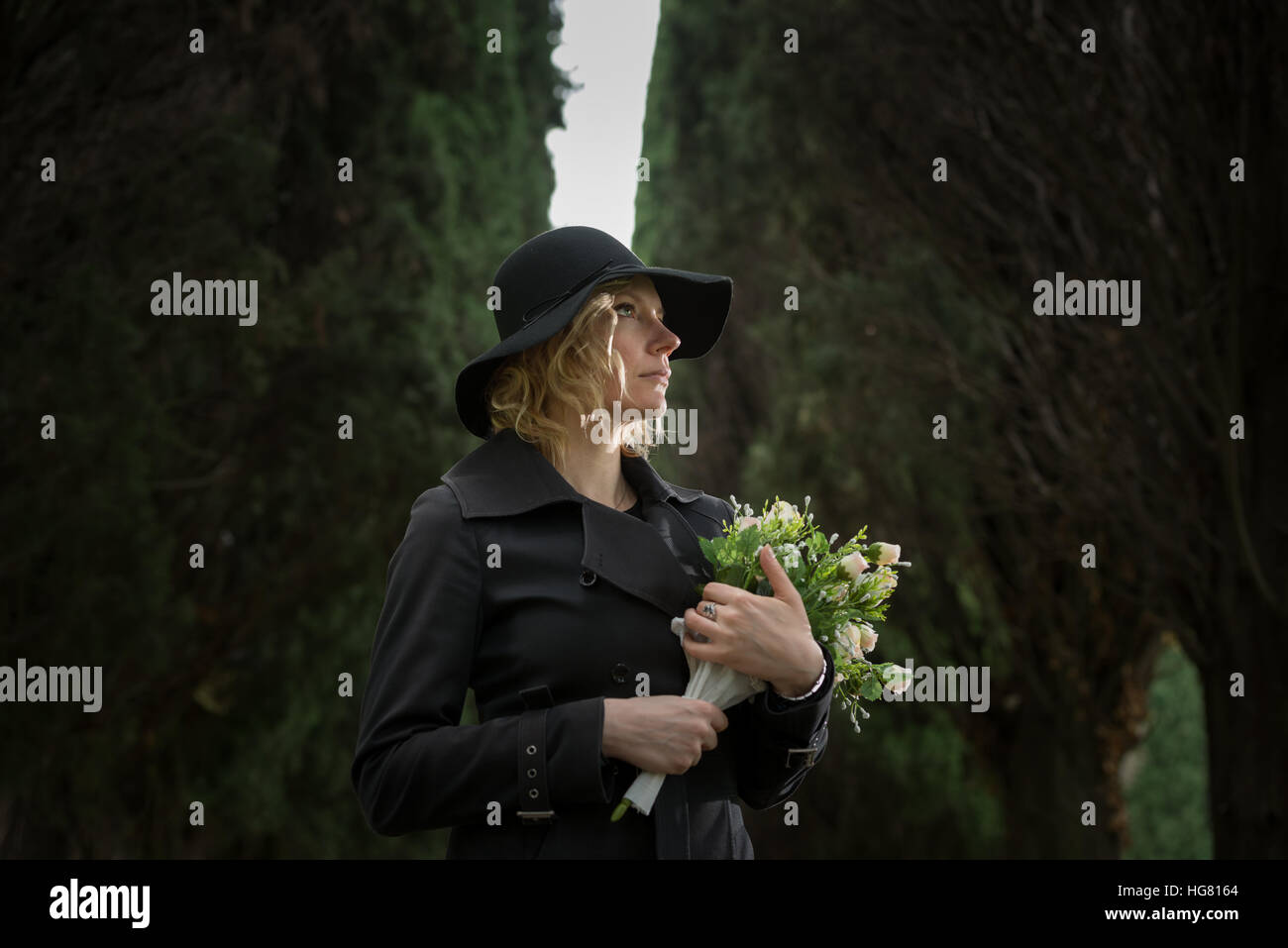 Close-up of a sad woman at cemetery holding flowers Stock Photo - Alamy
