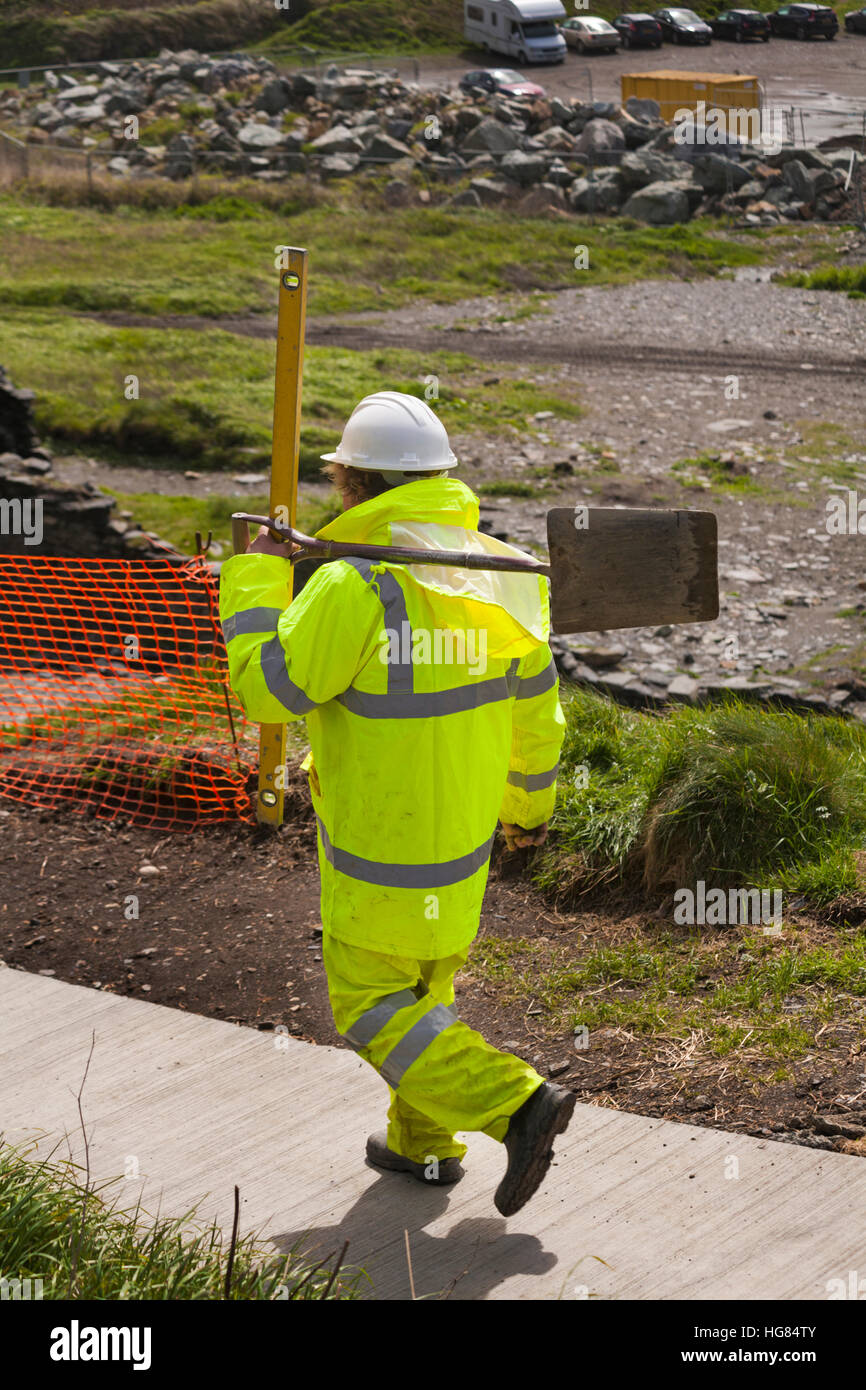 Workman carrying shovel and spirit level - workmen laying new path at ...