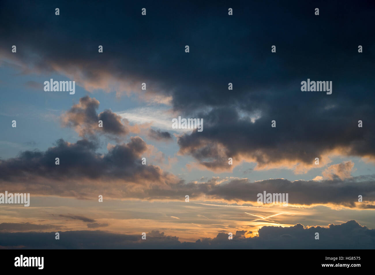 Golden sunset appearing from behind dark foreboding clouds Stock Photo ...