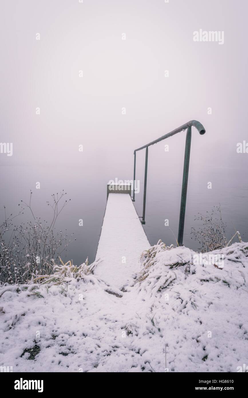Vertical photo of winter landscape with heavy morning fog. Footbridge ...