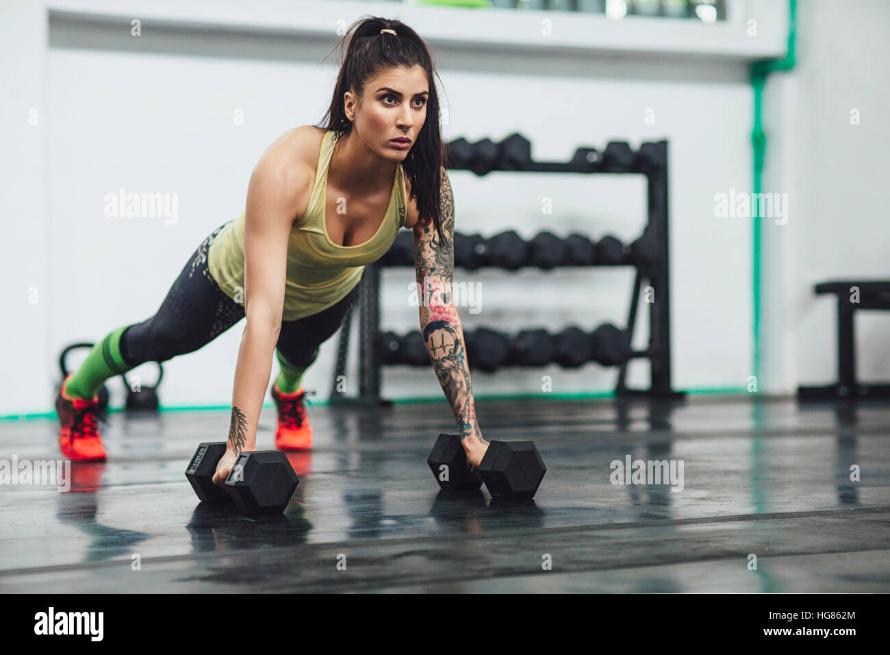 Confident athlete doing dumbbell push-ups in gym Stock Photo - Alamy