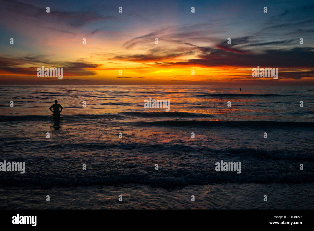 A stunning sunset over the ocean with person gazing Stock Photo - Alamy
