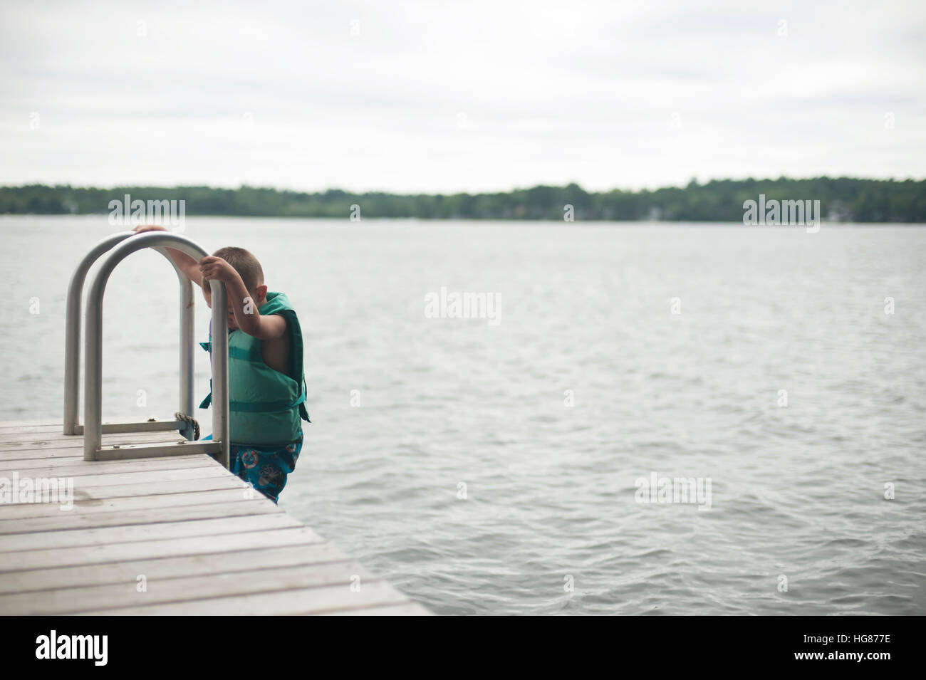 Boy climbing ladder of jetty against sky Stock Photo - Alamy