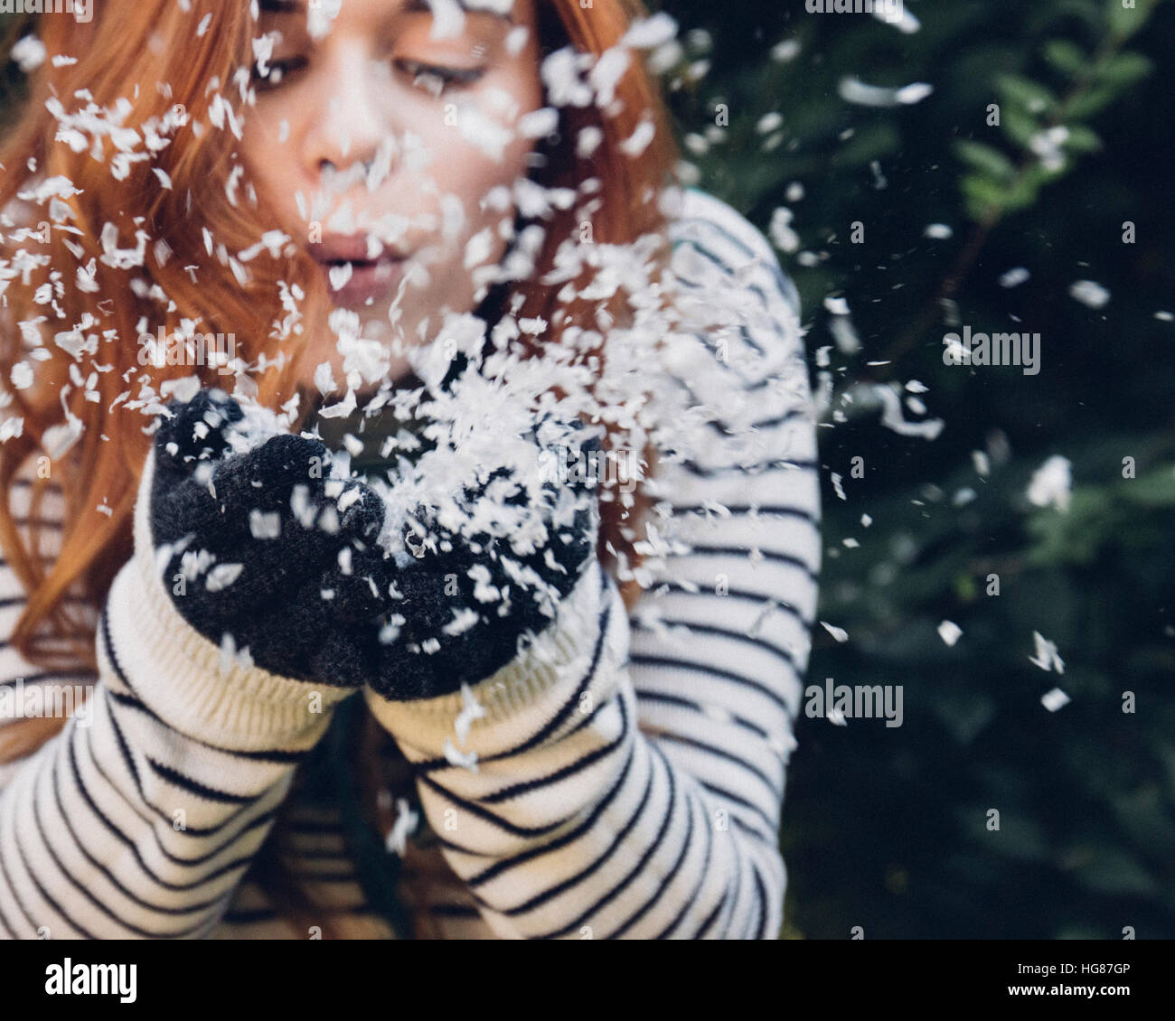 Playful woman blowing shredded papers while standing in backyard Stock ...