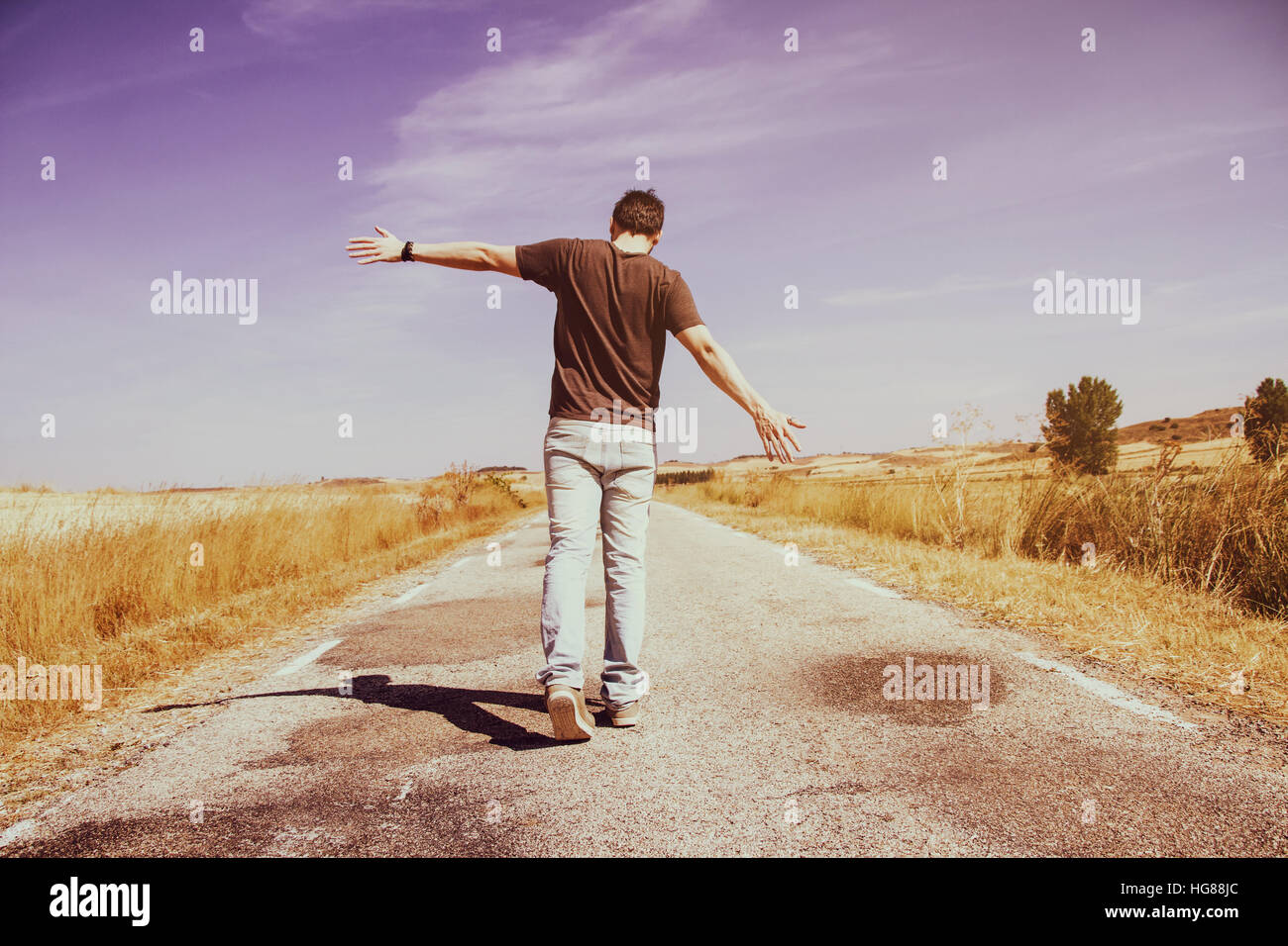 Young man walking over a old road Stock Photo - Alamy