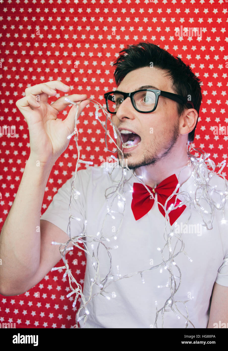 Young man in a funny photo biting christmas lights Stock Photo - Alamy