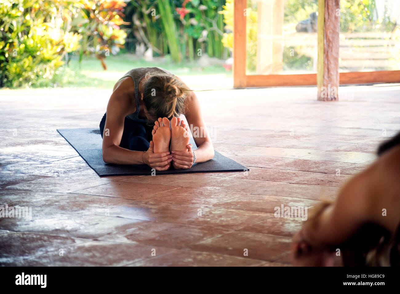 Woman practicing seated forward bend pose in yoga studio Stock Photo ... Woman practicing seated forward bend pose in yoga studio Stock Photo ...