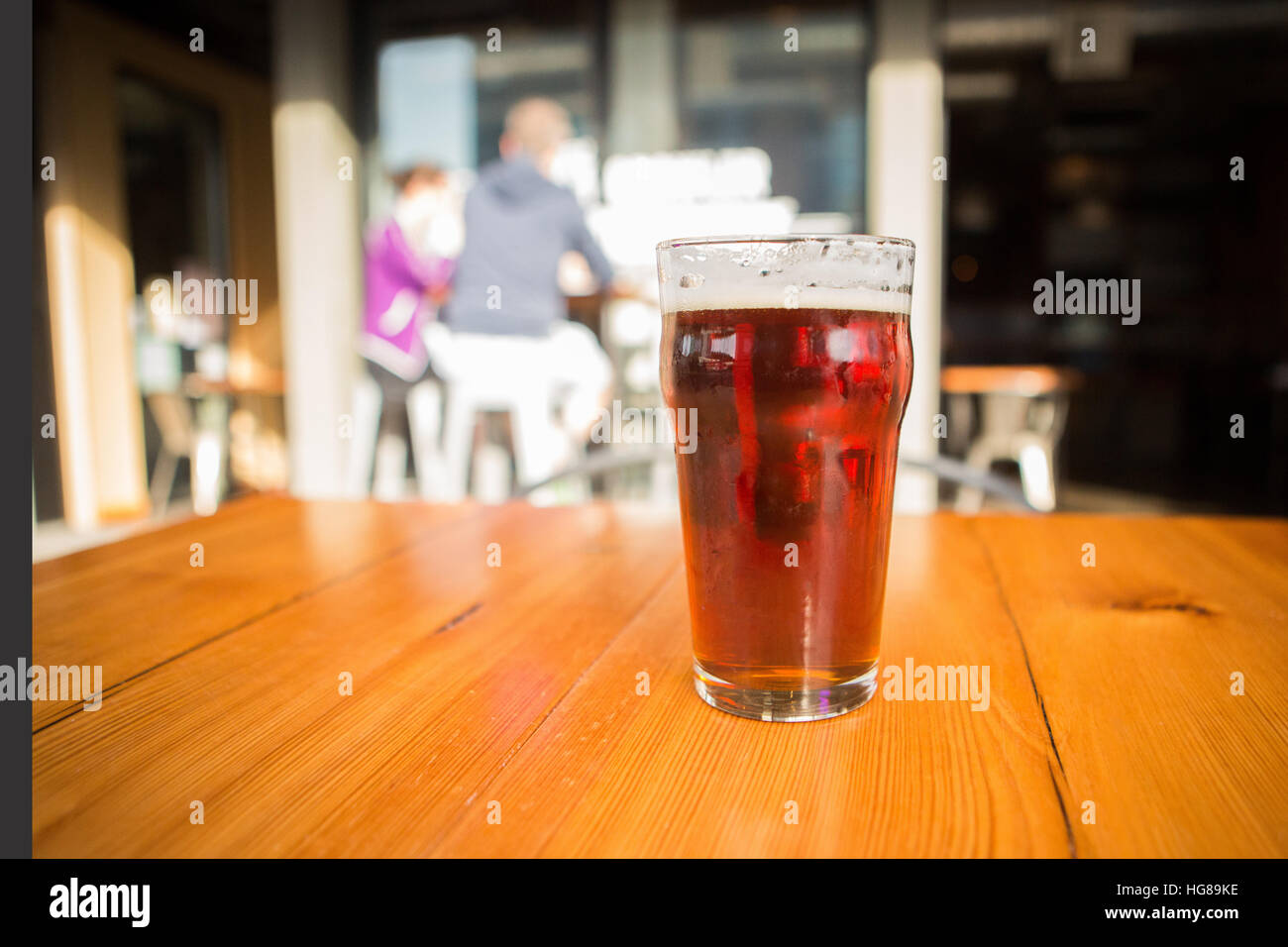 A pint glass filled with a craft beer or micro brew sits on a table ...