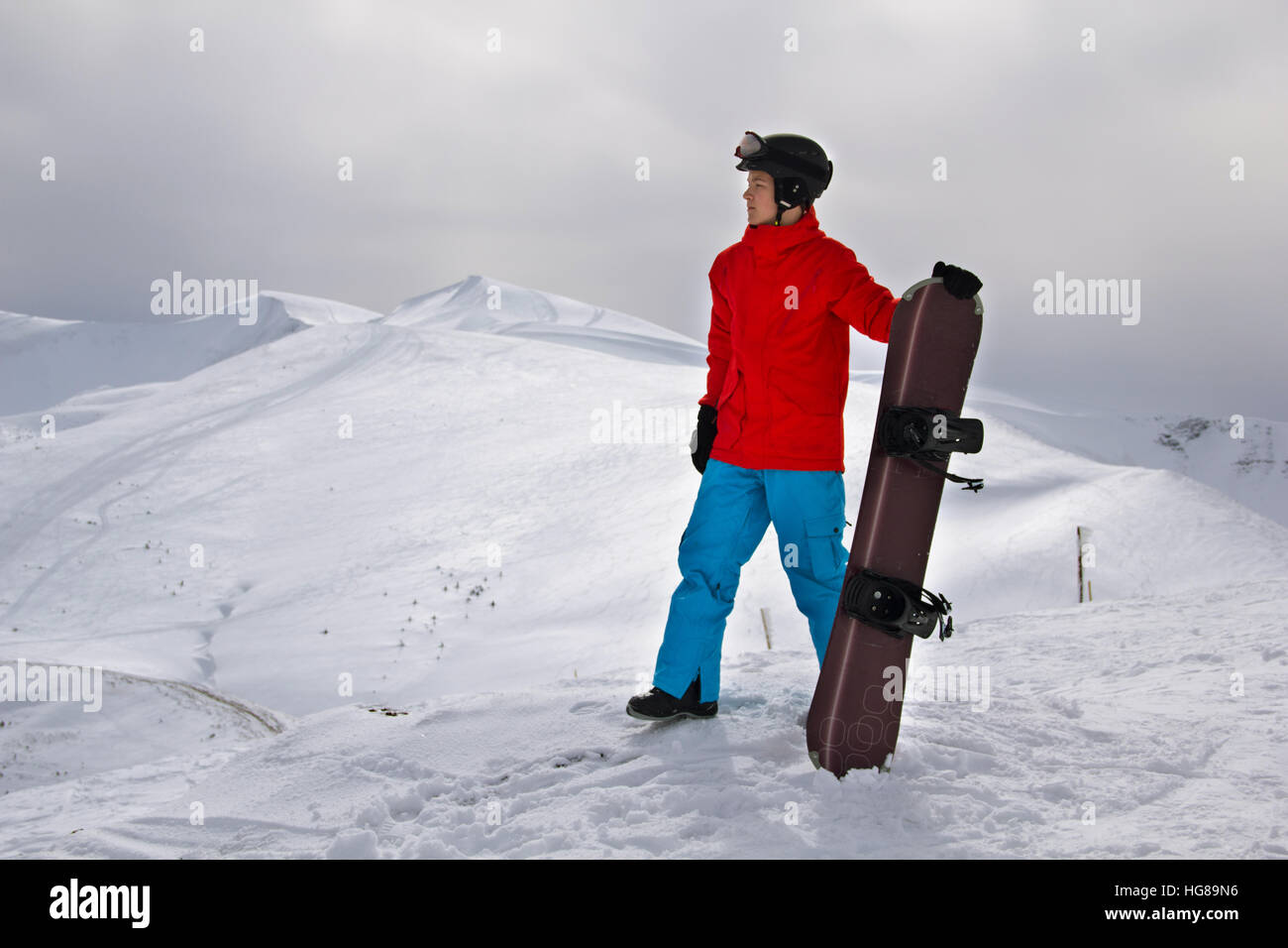 A young man with snowboard standing on a snowy mountain Stock Photo - Alamy