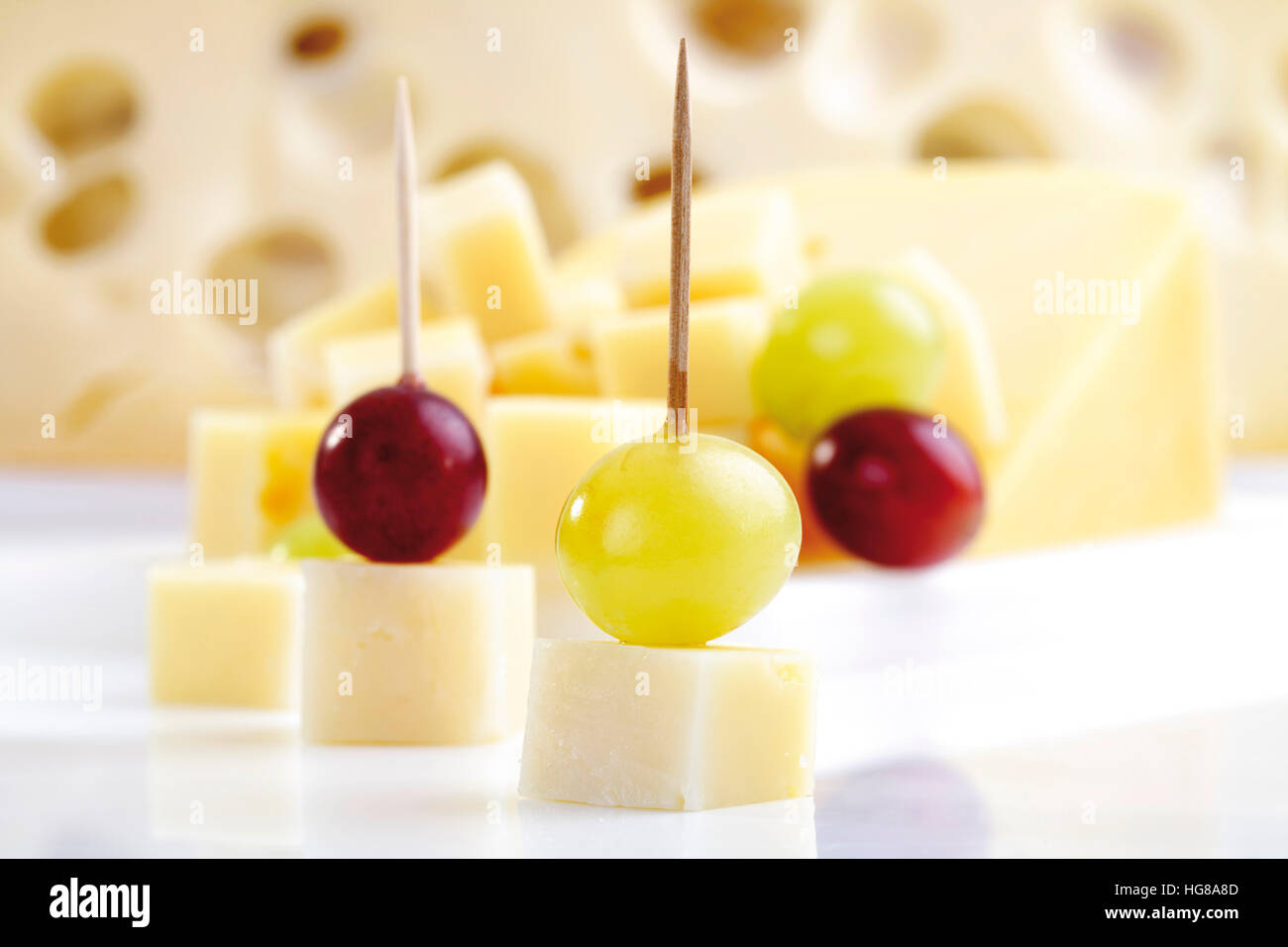 Diced cheese with grapes, half a cheese wheel in background Stock Photo ...
