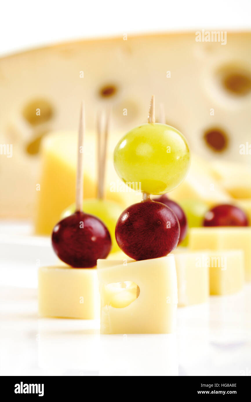 Diced cheese with grapes, half a cheese wheel in background Stock Photo ...