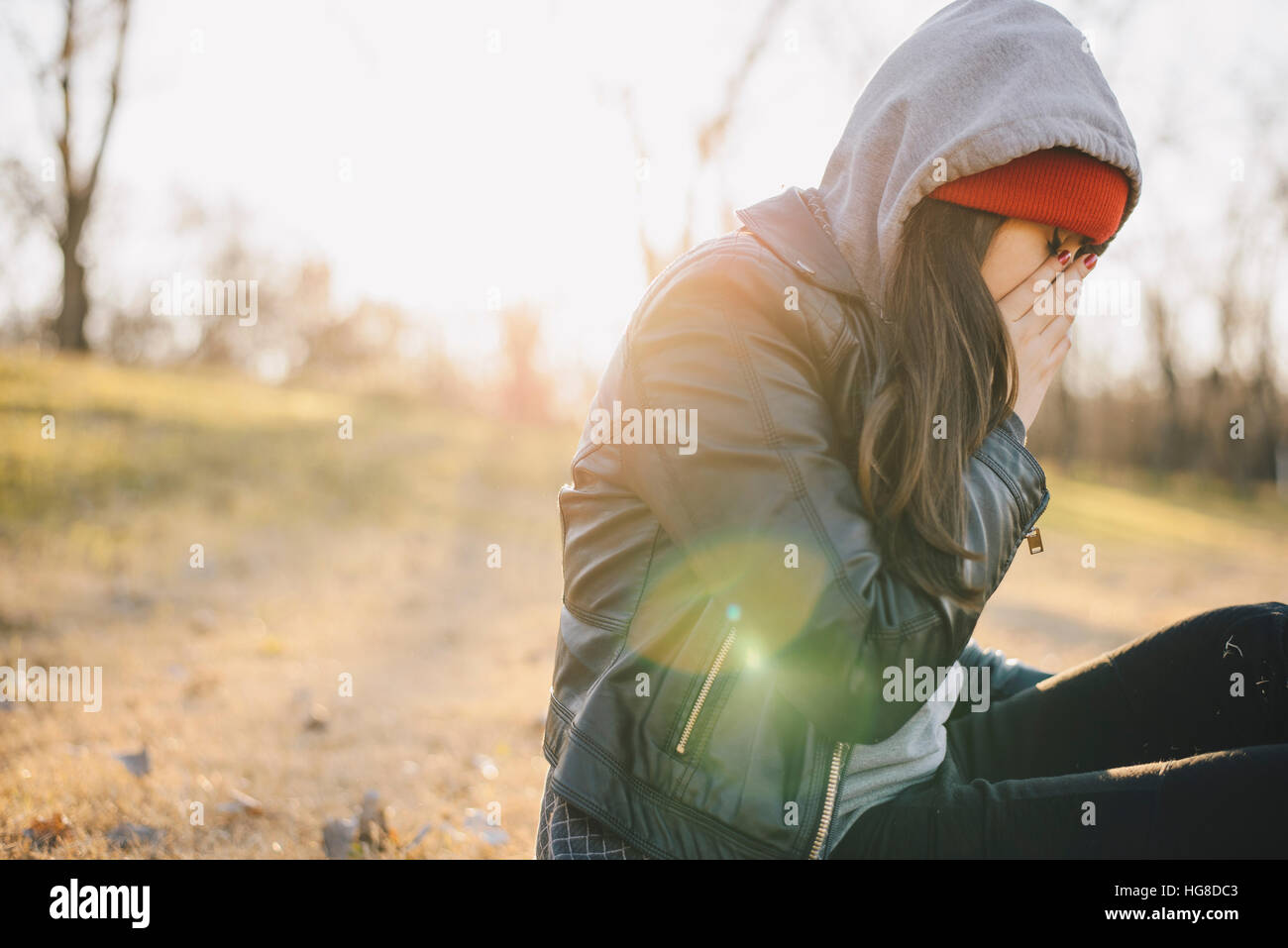 Sad woman sitting on field against sky Stock Photo - Alamy