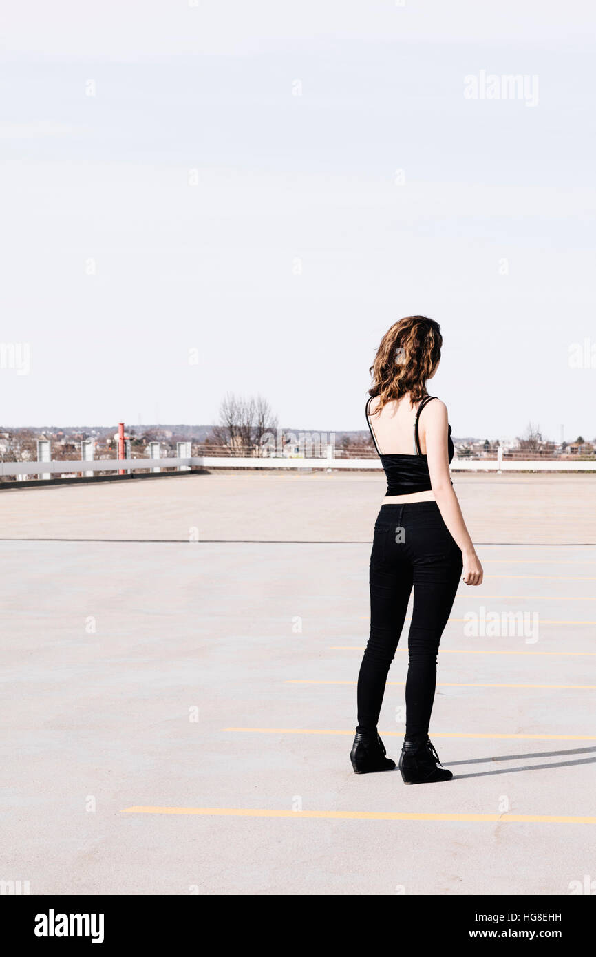 Rear view of woman standing on parking lot against clear sky Stock ...