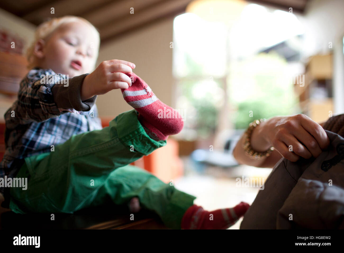 Low angle view of boy removing socks while mother holding backpack at ...