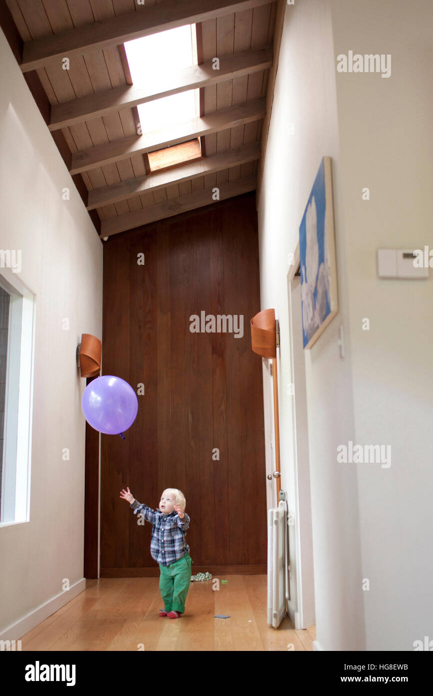 Curious boy trying to catch balloon at home Stock Photo - Alamy