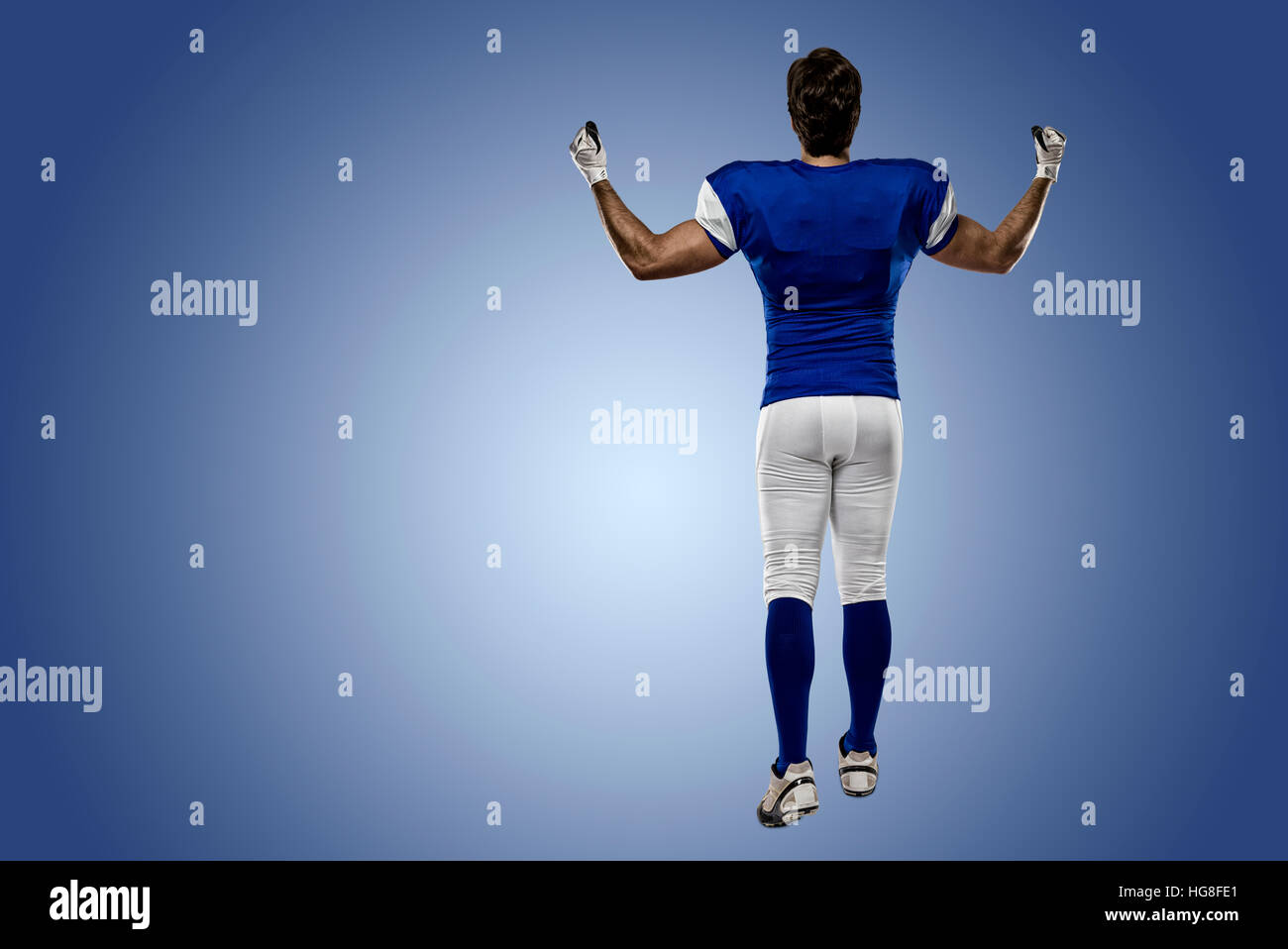 Football Player with a blue uniform walking, showing his back on a blue ...