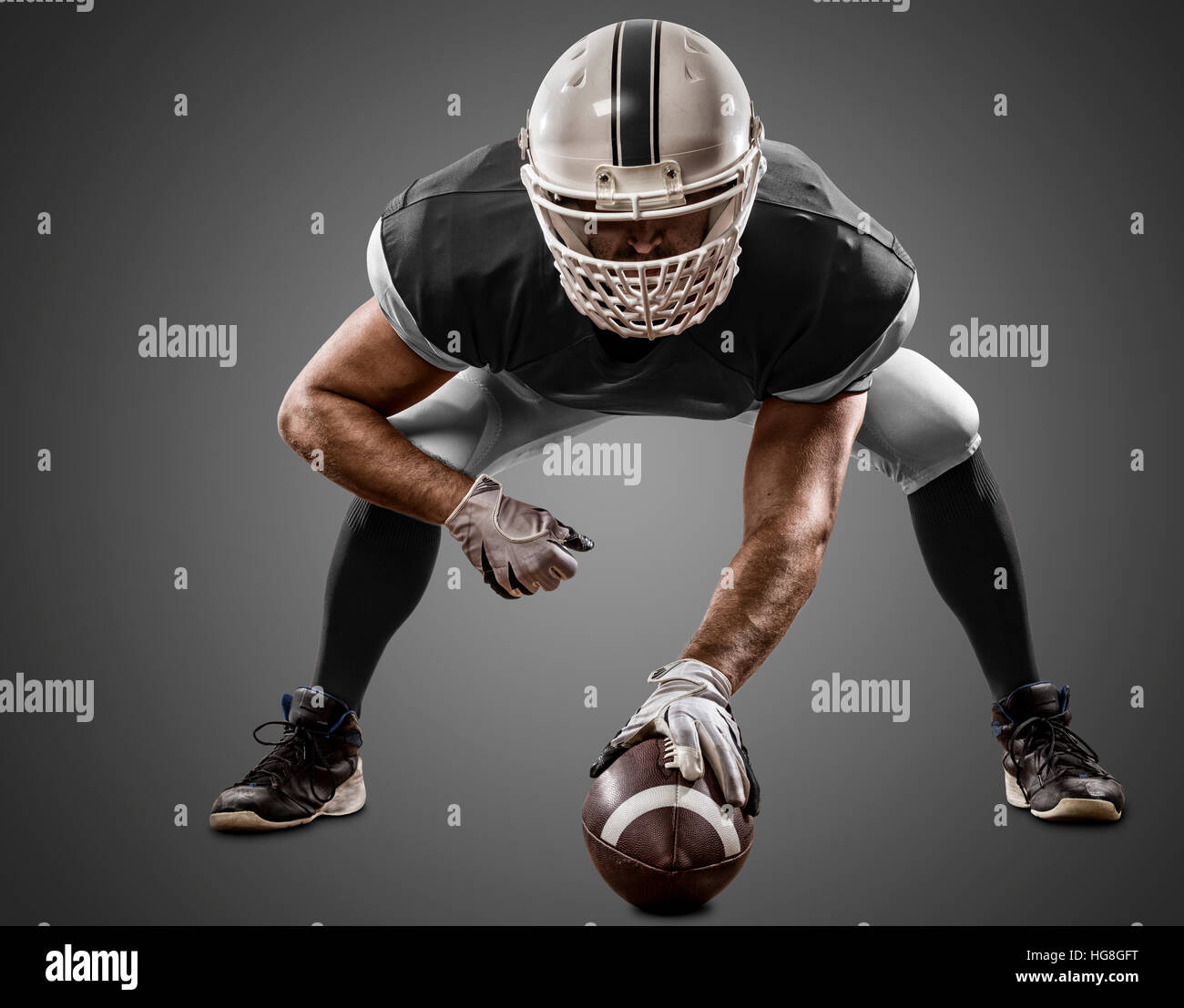 Football Player with a black uniform on the scrimmage line, on a black ...