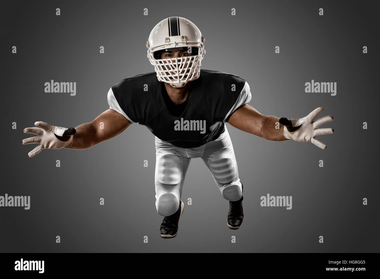 Football Player with a black uniform making a tackle on a black ...