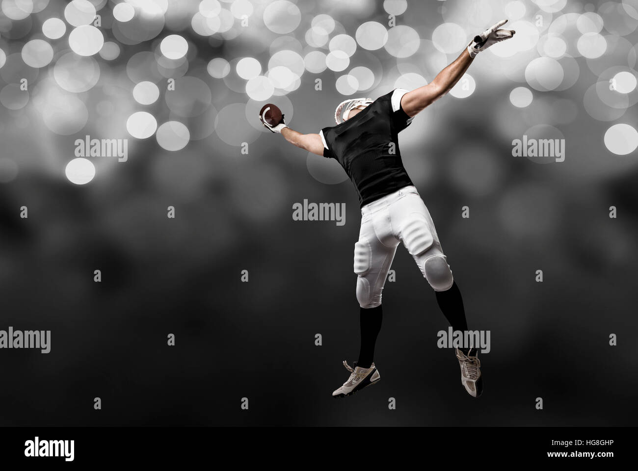 Football Player with a black uniform making a catch on a black lights ...