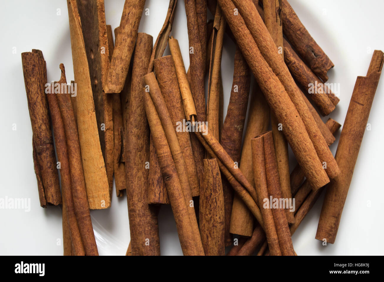 A pile of cinnamon sticks on a white plate, photographed from above ...