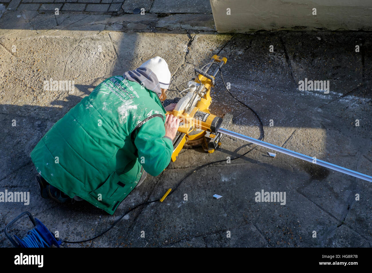 builder cutting aluminium edging strip to size on a cutting machine ...