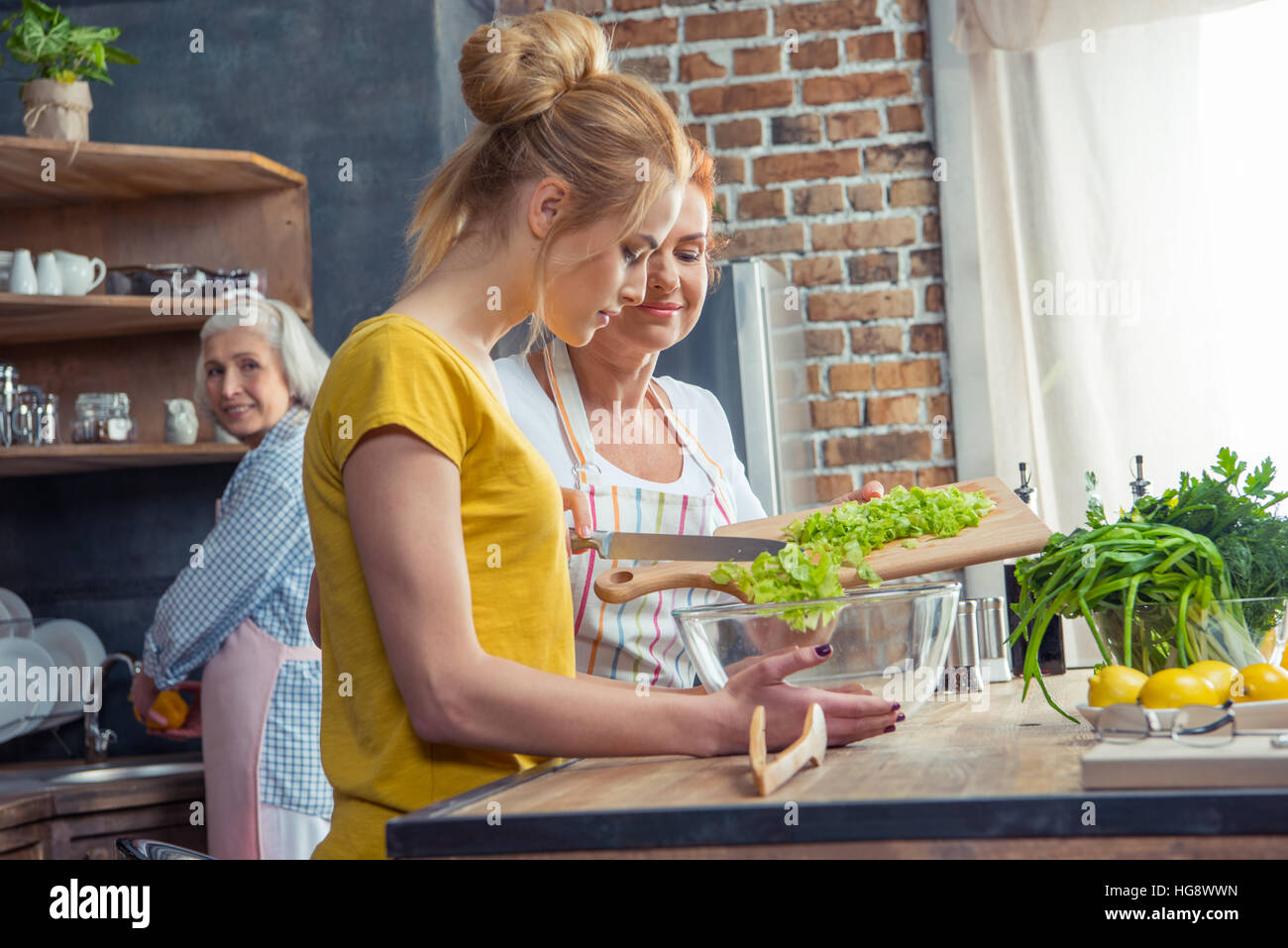 Happy family cooking together vegetable salad in kitchen Stock Photo ...