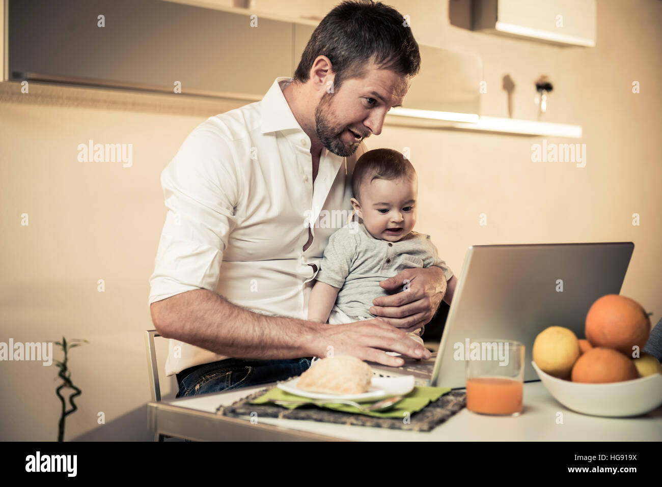 Multi-tasking father with baby while working at home Stock Photo - Alamy