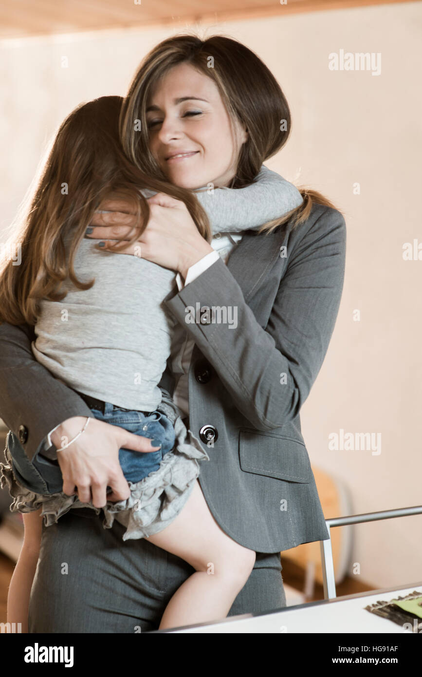 Mother embracing her little girl before leaving to work/or just back ...
