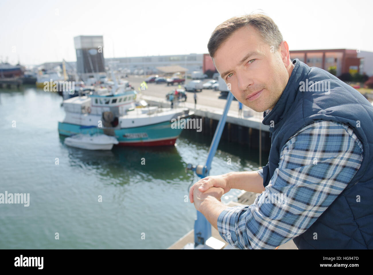 Man leaning on railing on harbour Stock Photo - Alamy