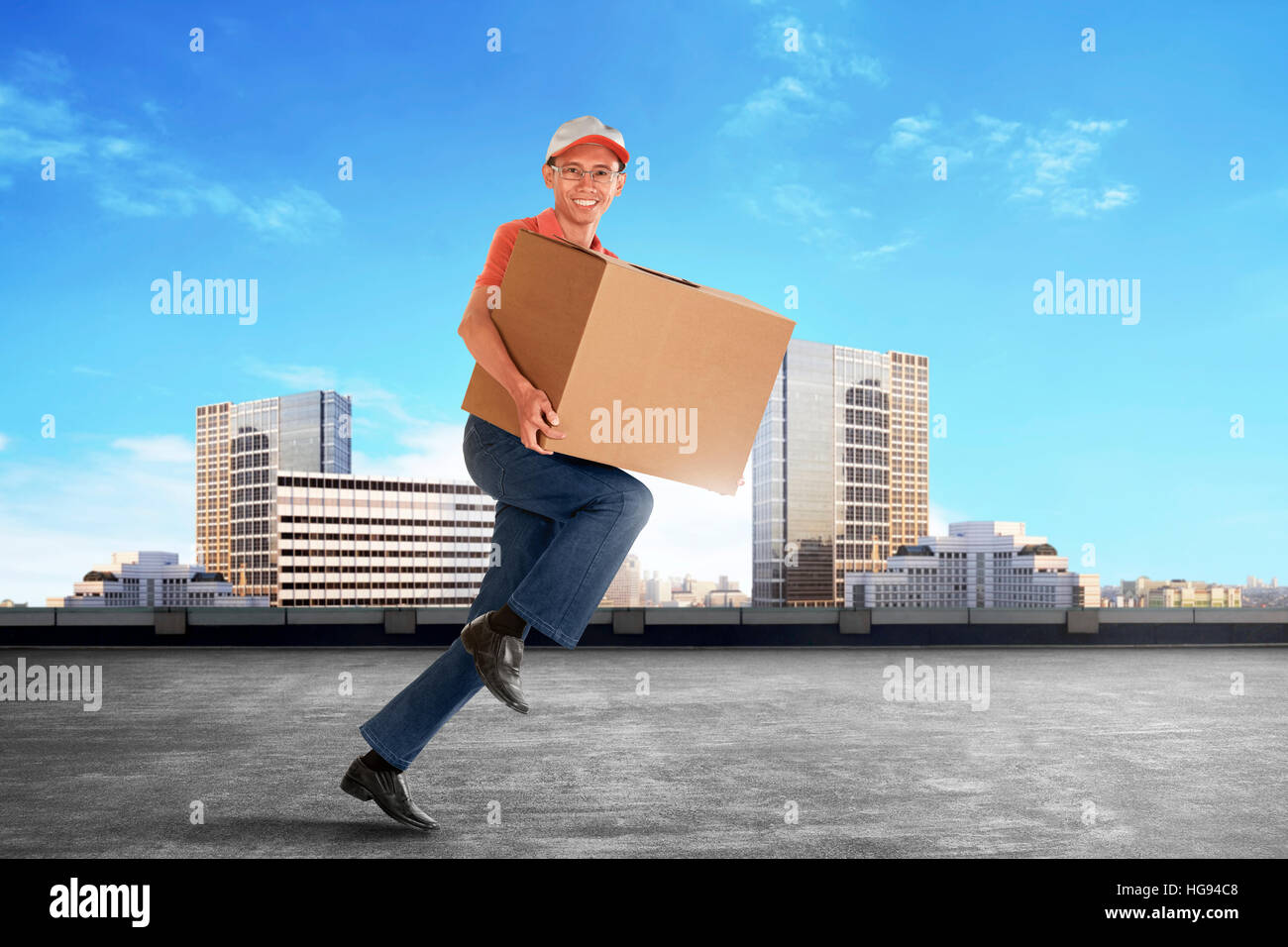 Cheerful young asian courier holding a cardboard box running against ...