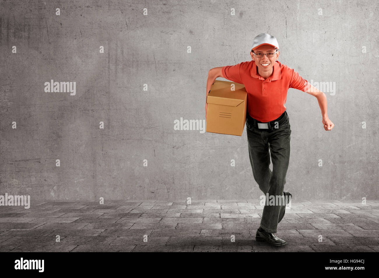 Asian delivery courier holding package running over gray background ...