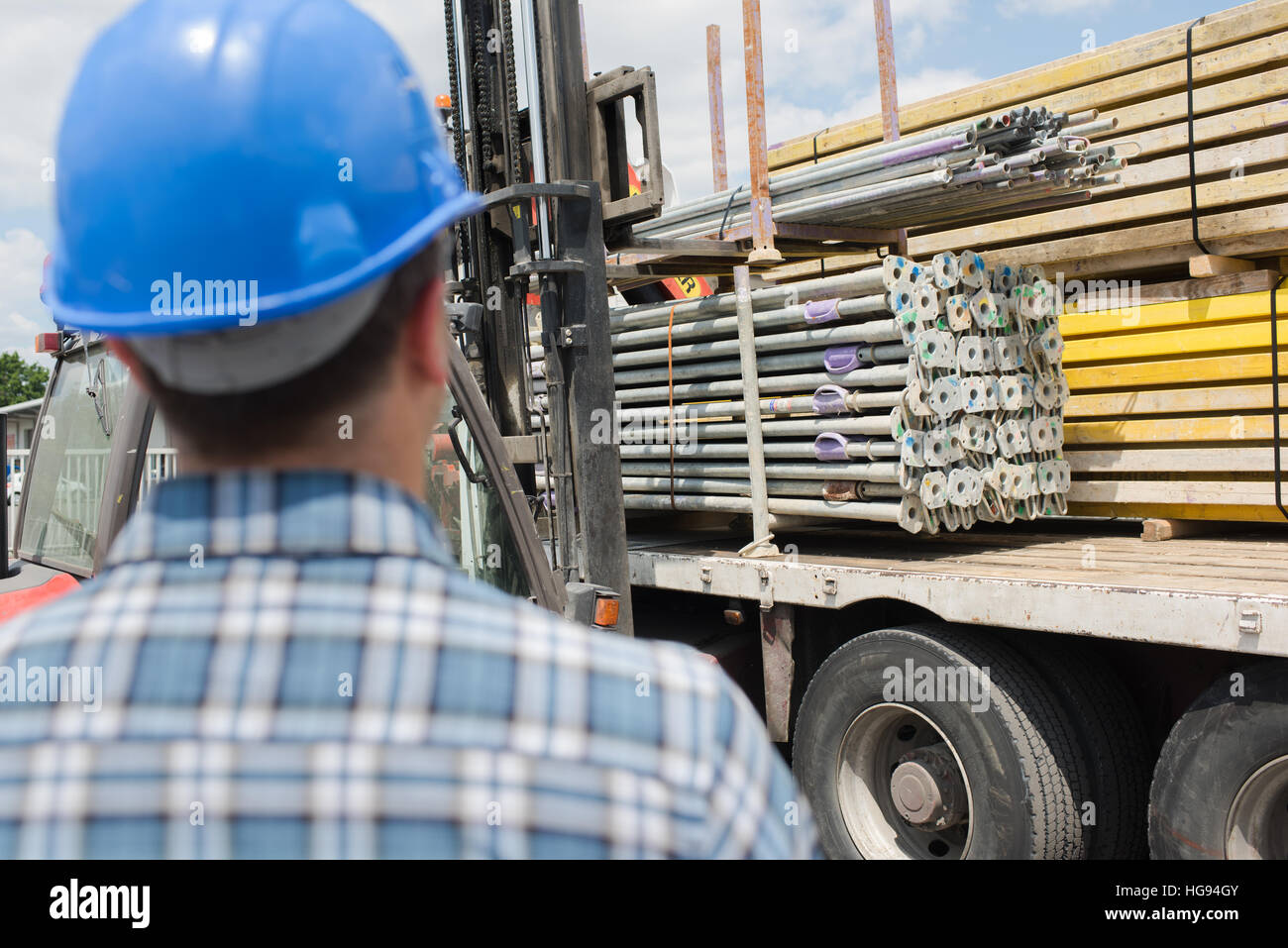Rear view of man looking at lorry load of materials Stock Photo - Alamy