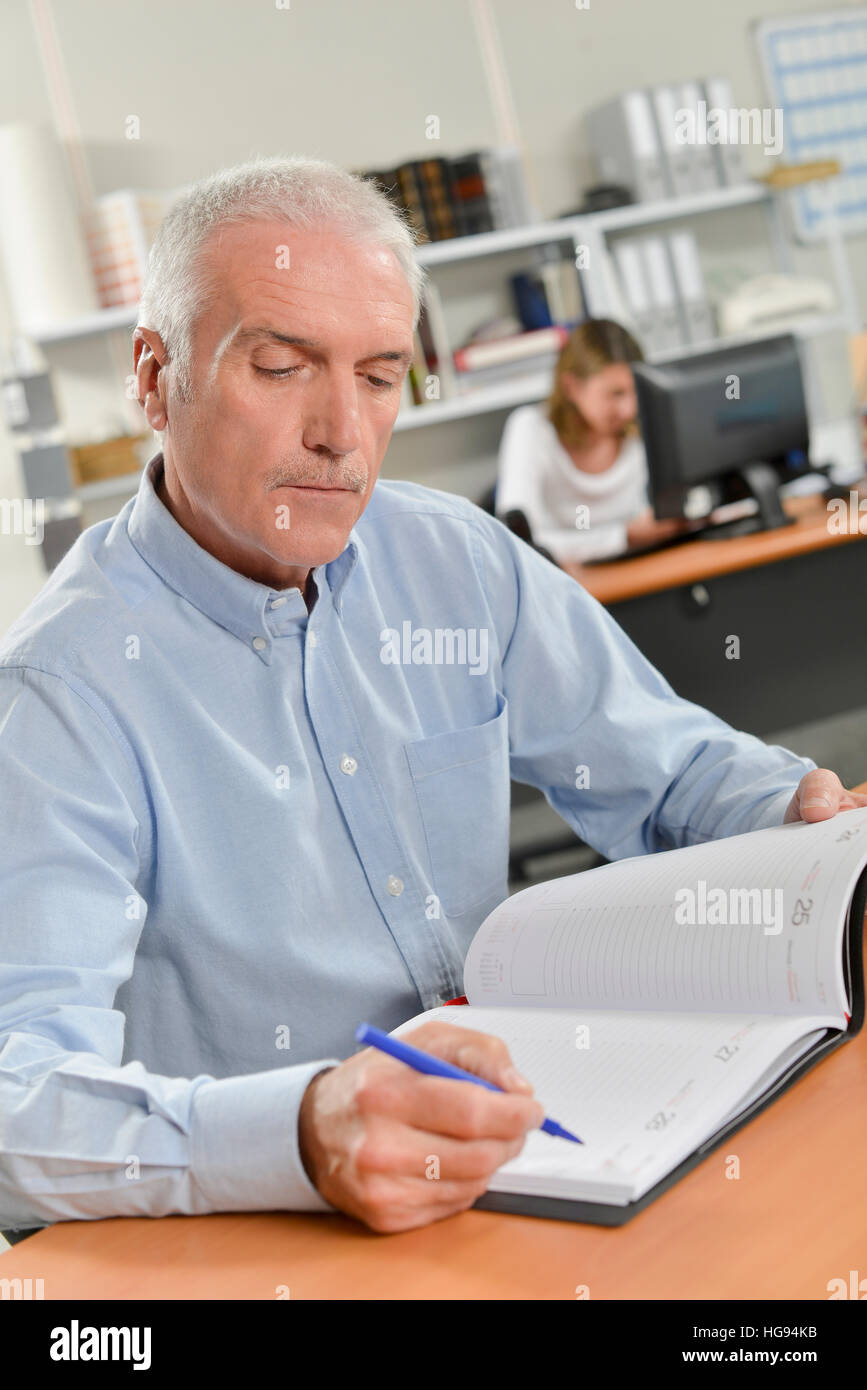 man in office filling book Stock Photo - Alamy
