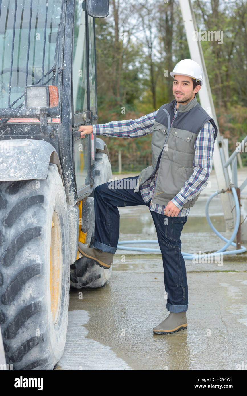 Man climbing into construction vehicle Stock Photo - Alamy