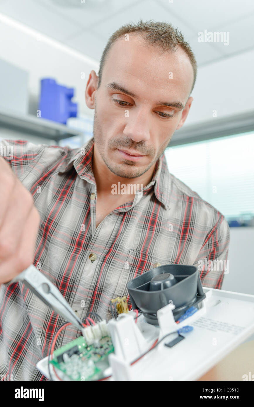 Man using long nose pliers on back of electrical appliance Stock Photo ...