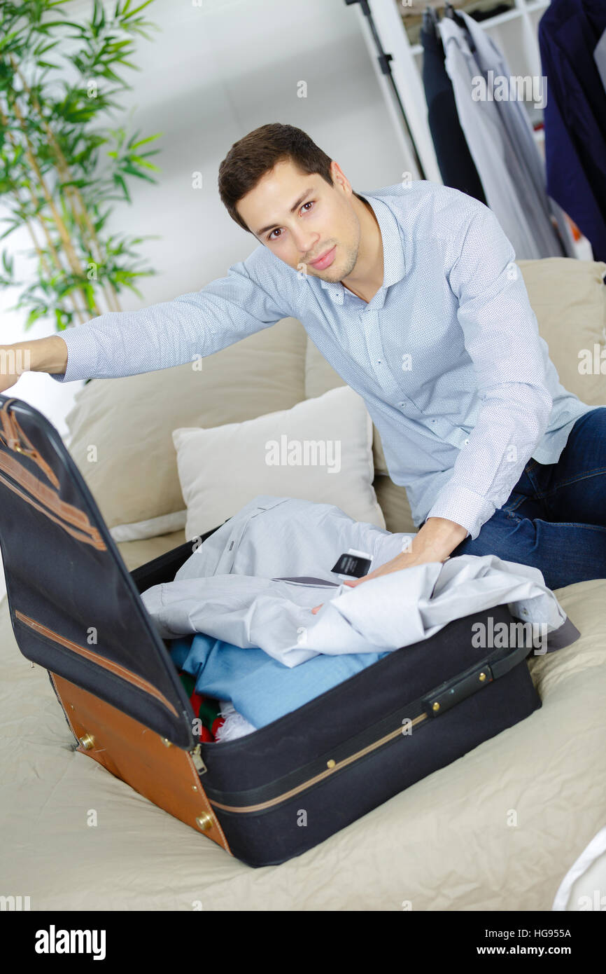young man unpacking suitcase in hotel room Stock Photo - Alamy