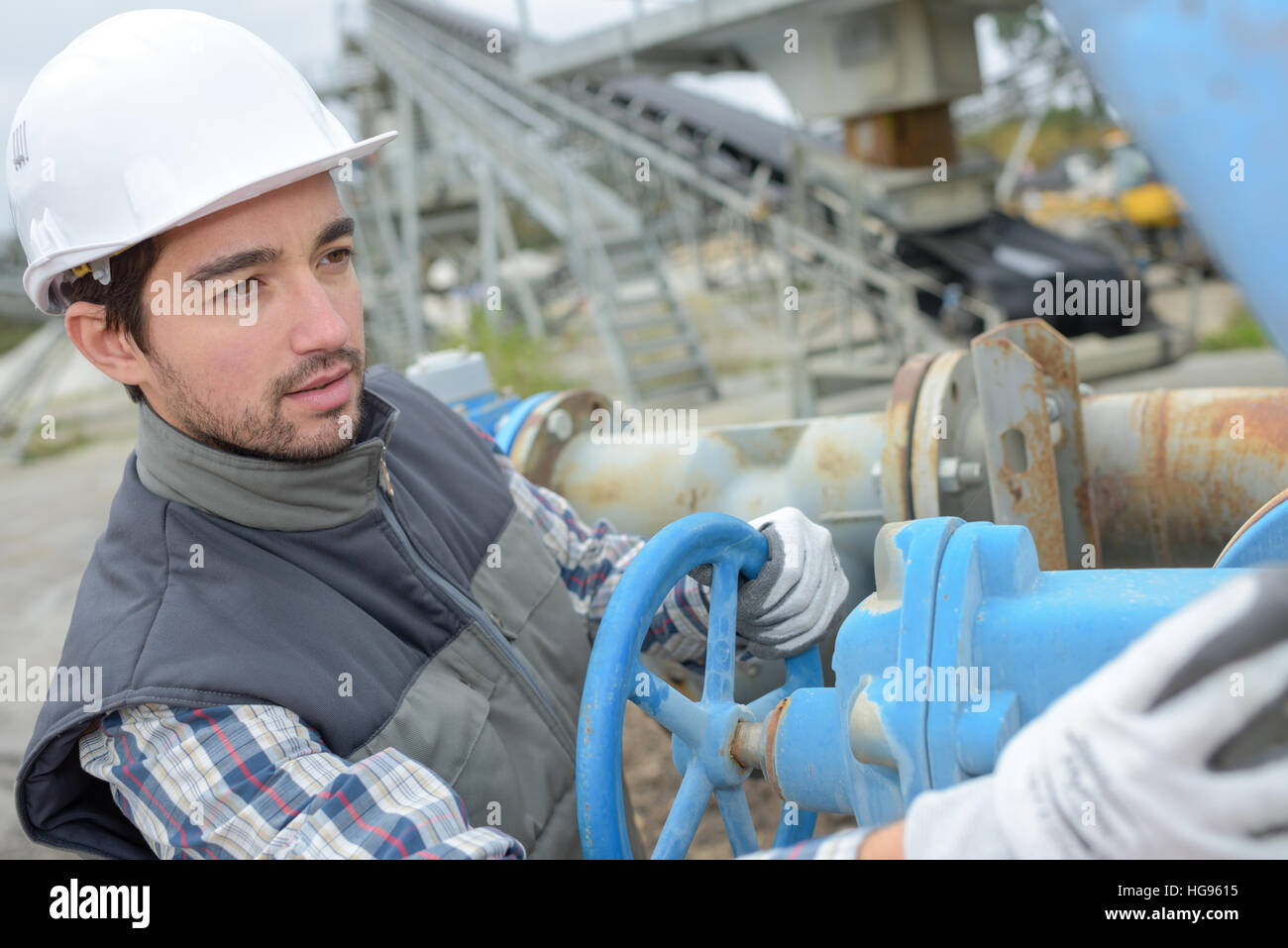 Worker turning wheel on machine Stock Photo - Alamy