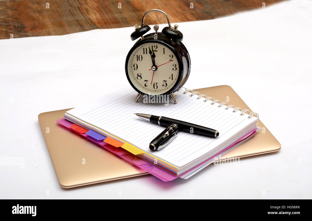 Alarm Clock on Book with laptop and pen Stock Photo - Alamy