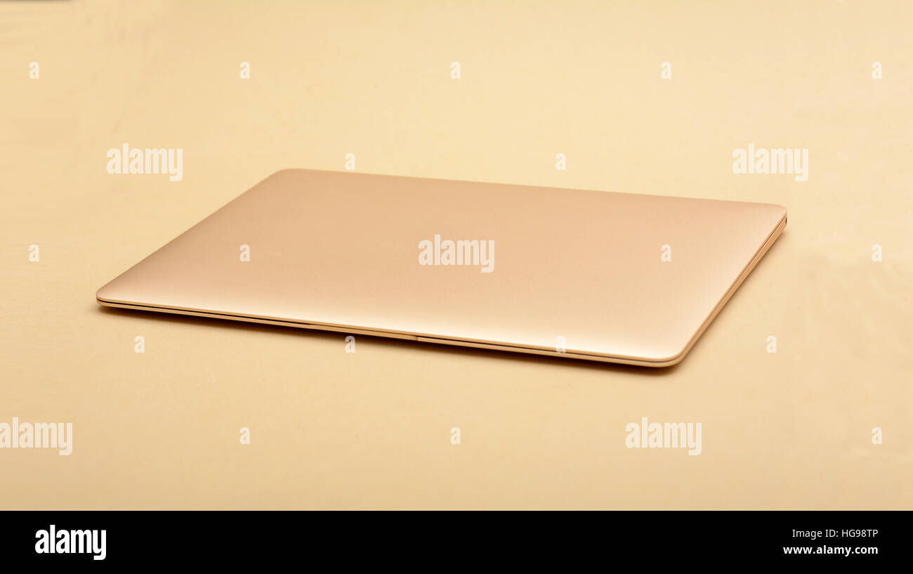 Smart Gold color laptop closed on golden background Stock Photo - Alamy
