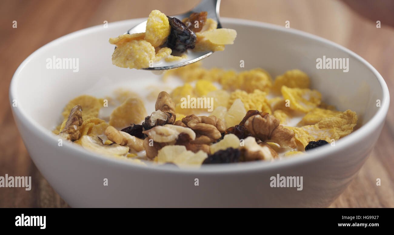 closeup eating with a spoon breakfast with corn flakes and mix of nuts ...