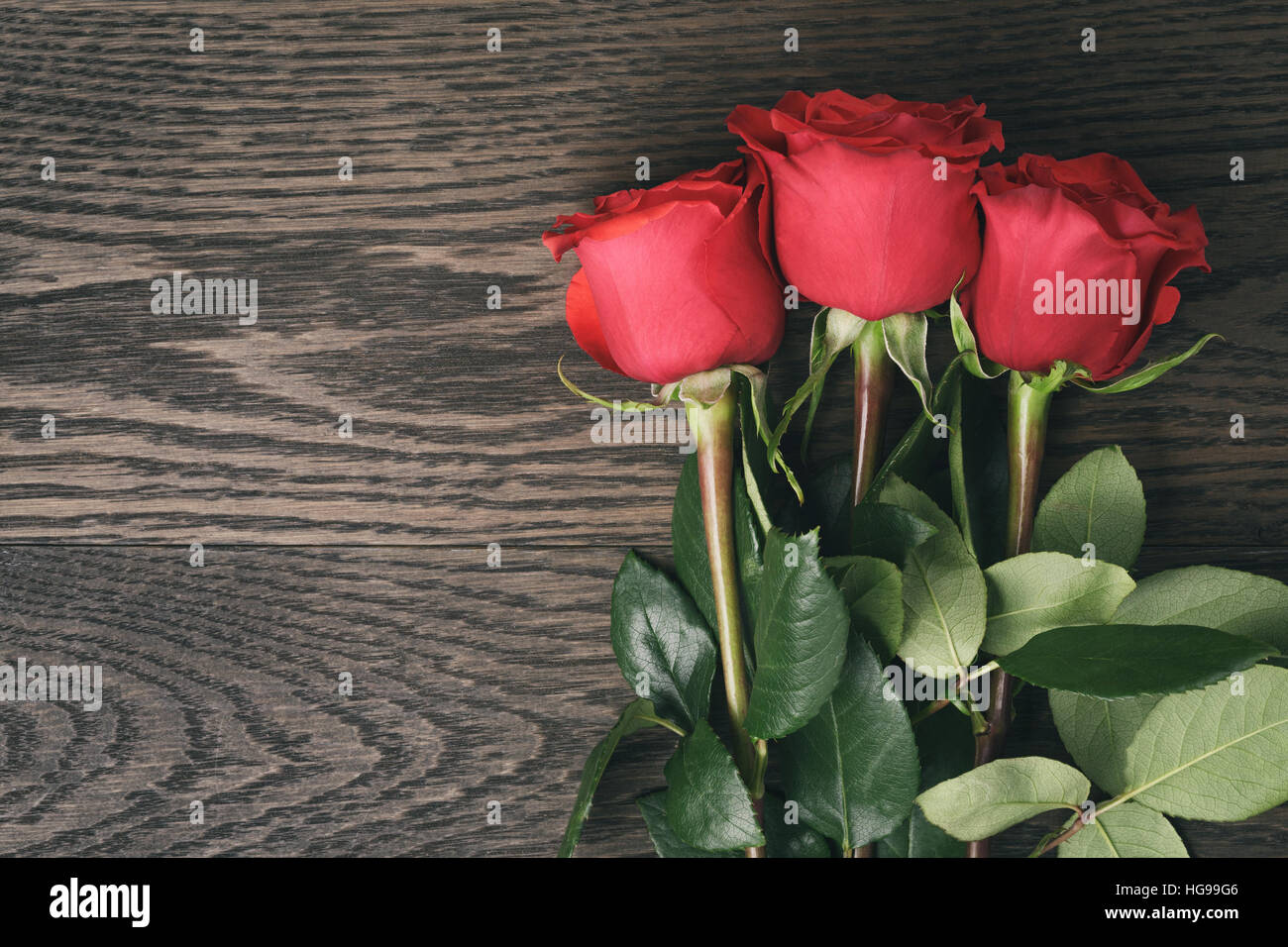 romantic background with three red roses on wood table from above Stock ...