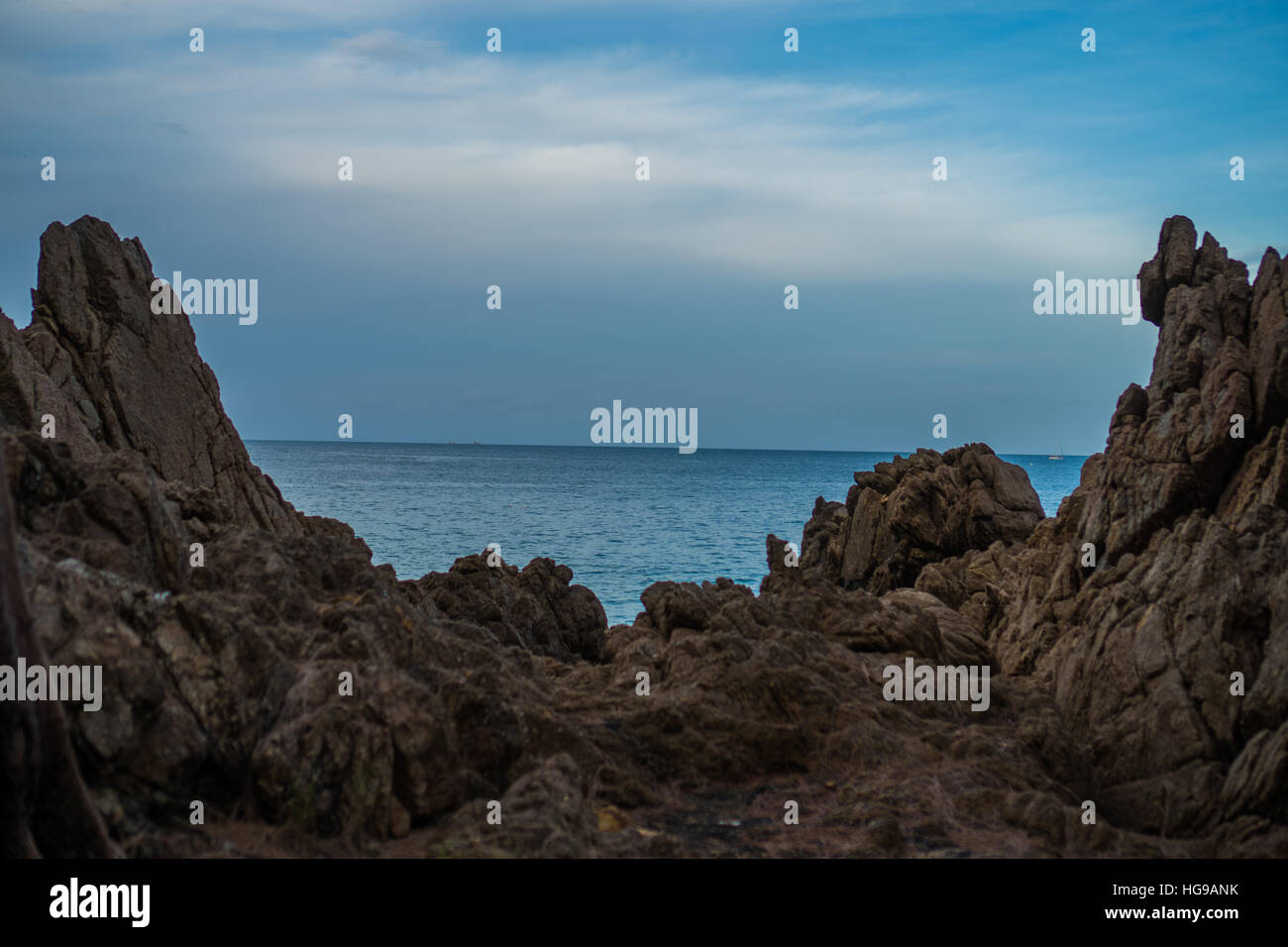 Closeup large formation of rocks on shoreline between beach and sea ...